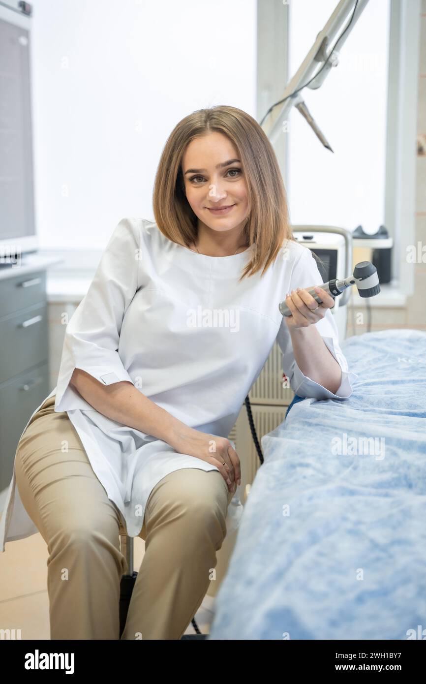 Pretty woman dermatologist with dermatoscope in uniform and gloves in ...