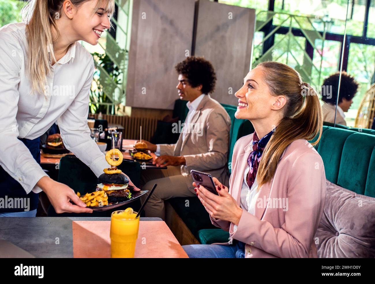 Smiling waitress serving meal to businesswoman in restaurant Stock ...
