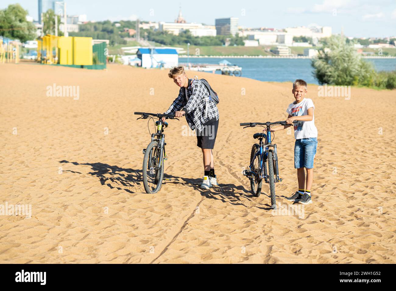 Two exhausted boys in casual clothing dragging their bicycles across ...