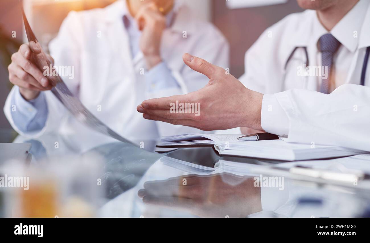 Two doctors look at x-rays and discuss the diagnosis. They sit a Stock ...