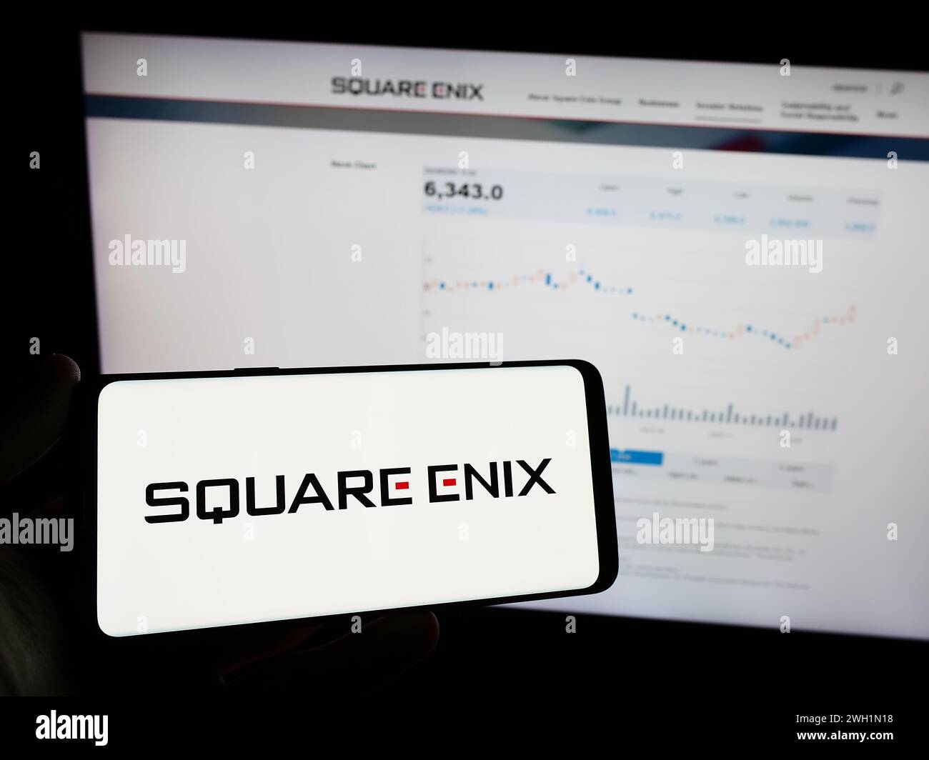 Person holding mobile phone with logo of Japanese gaming company Square ...