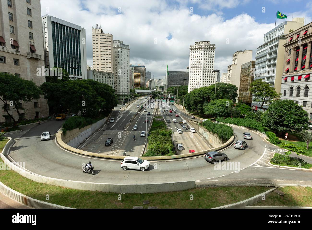 cars pass through a half-moon street crossing a busy avenue, in the ...