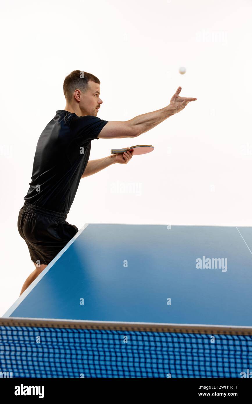 Side view portrait of young athlete man serving ball in table tennis ...