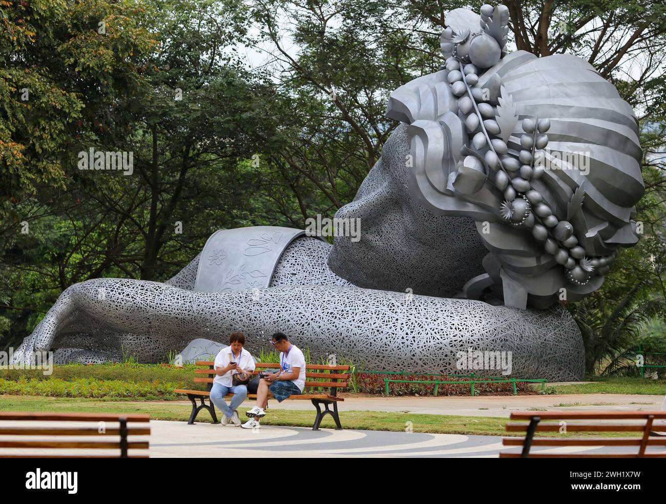 Laos. 26th Jan, 2024. Visitors sit in front of statue in the garden in ...