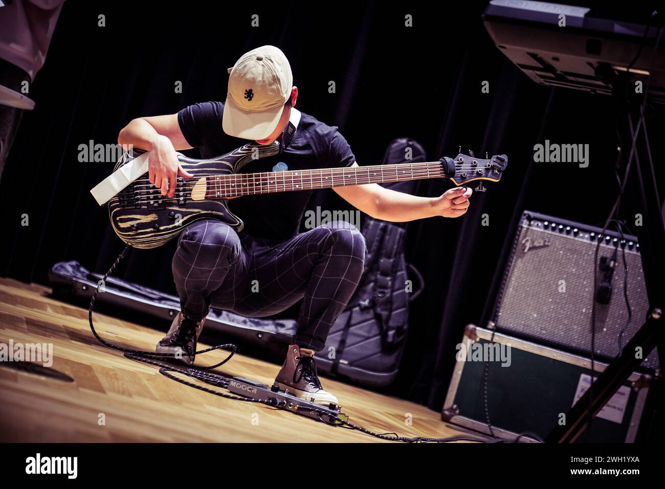 A bass player tuning his bass on stage Stock Photo - Alamy