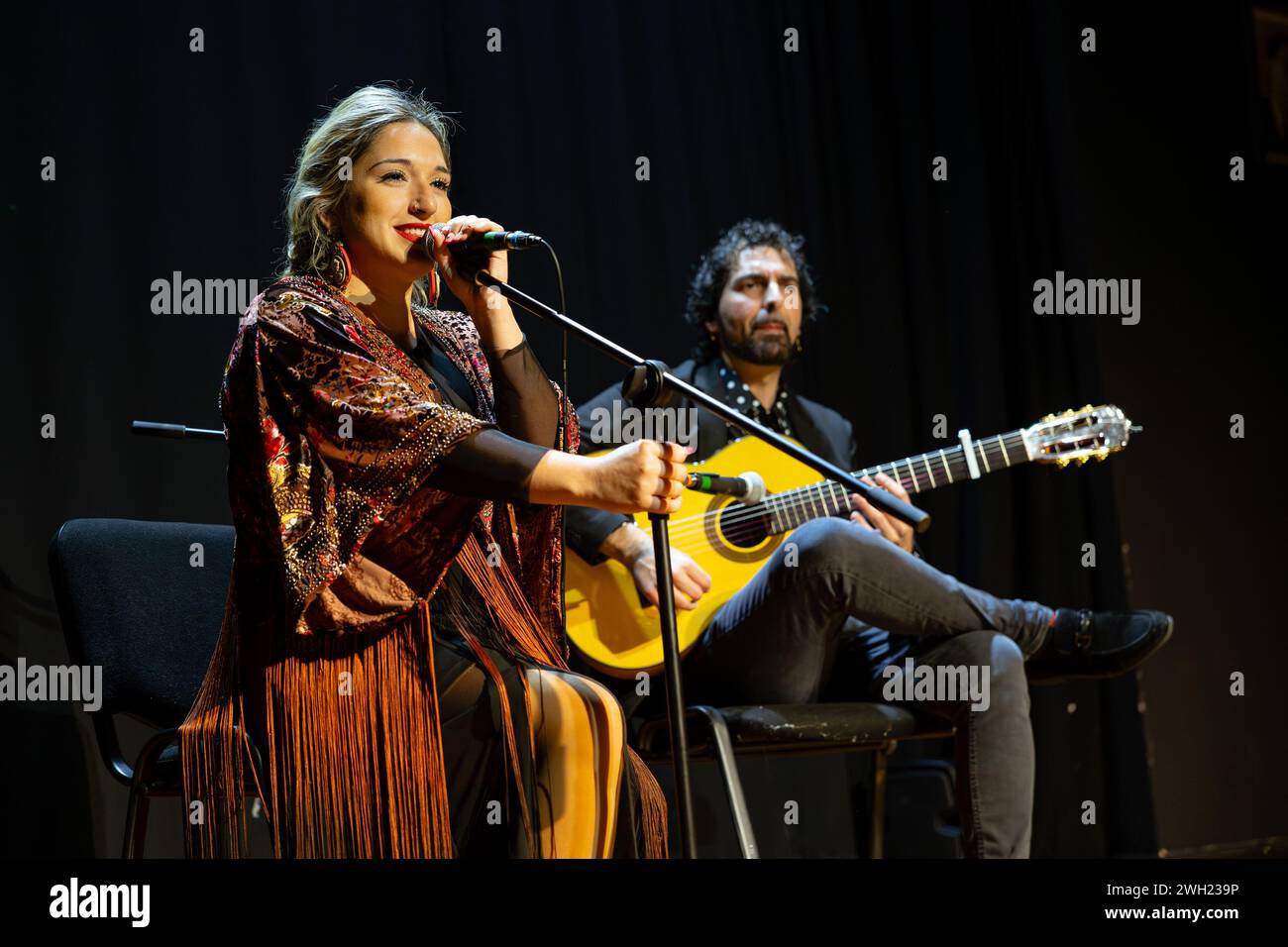 "Female flamenco singer performing with male guitarist on a dimly lit ...