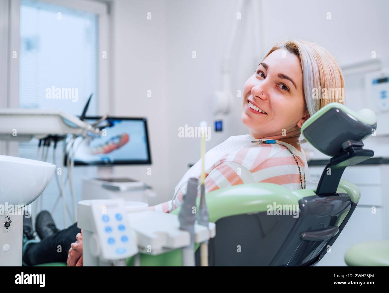 Portrait of young smiling woman sitting in stomatology clinic chair ...