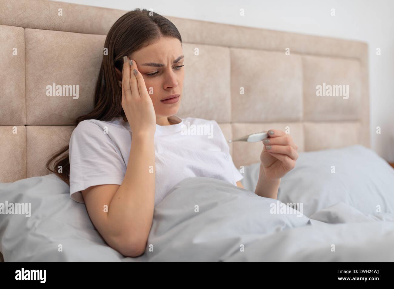 Sick woman in bed checking temperature with thermometer Stock Photo - Alamy