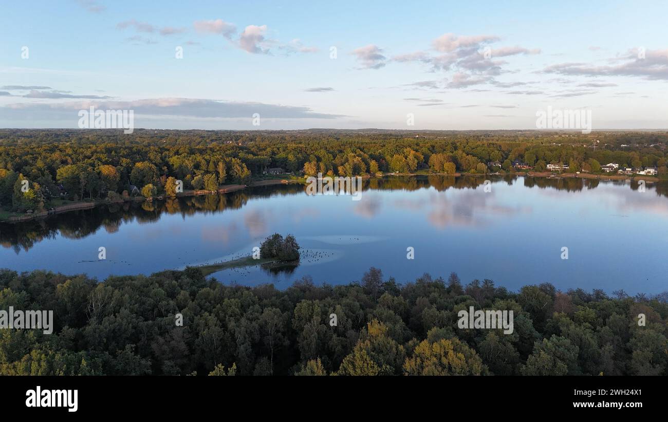 A serene lake nestled amidst a lush forest with dramatic clouds ...