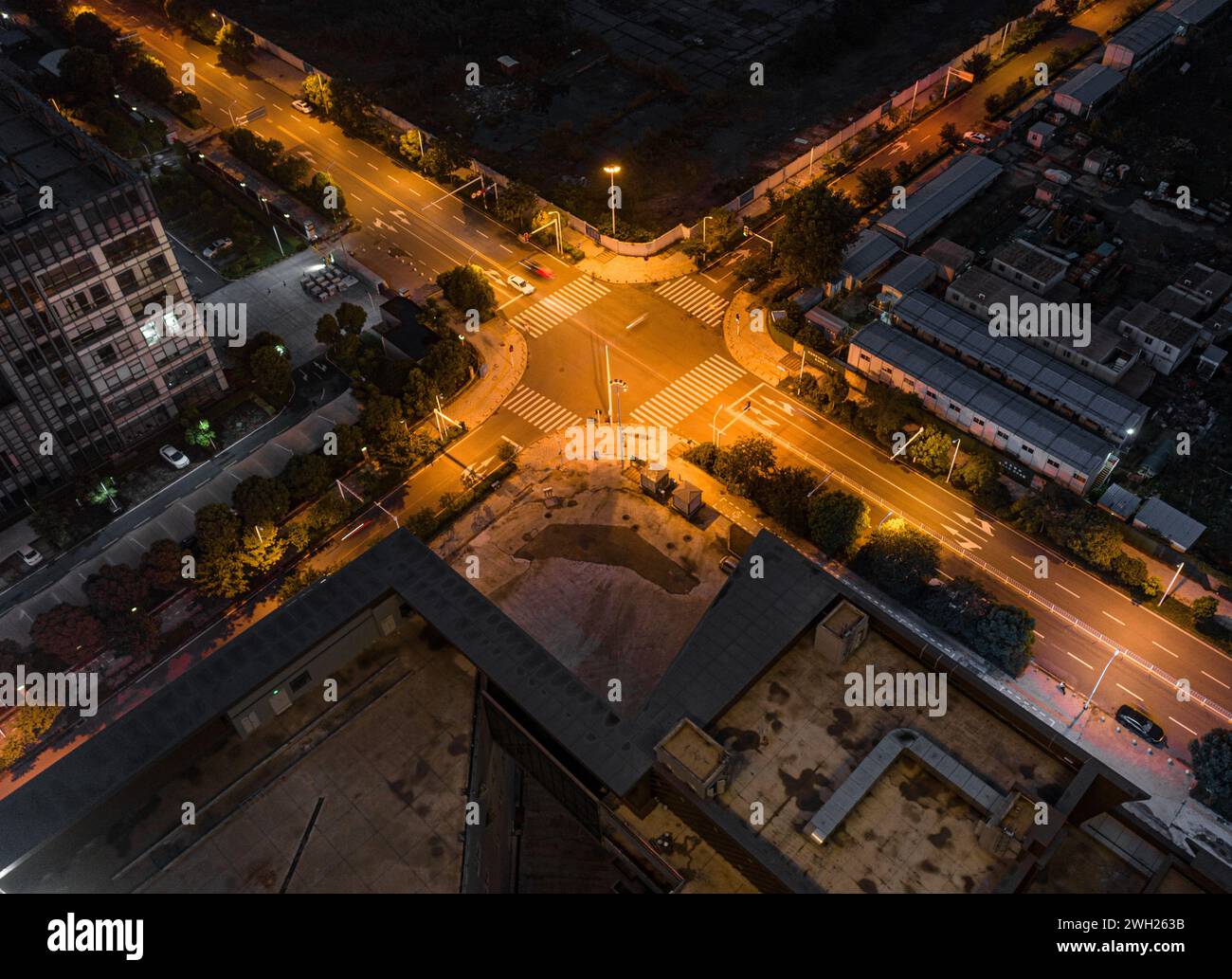 An aerial view of an intersection illuminated by orange-yellow street ...