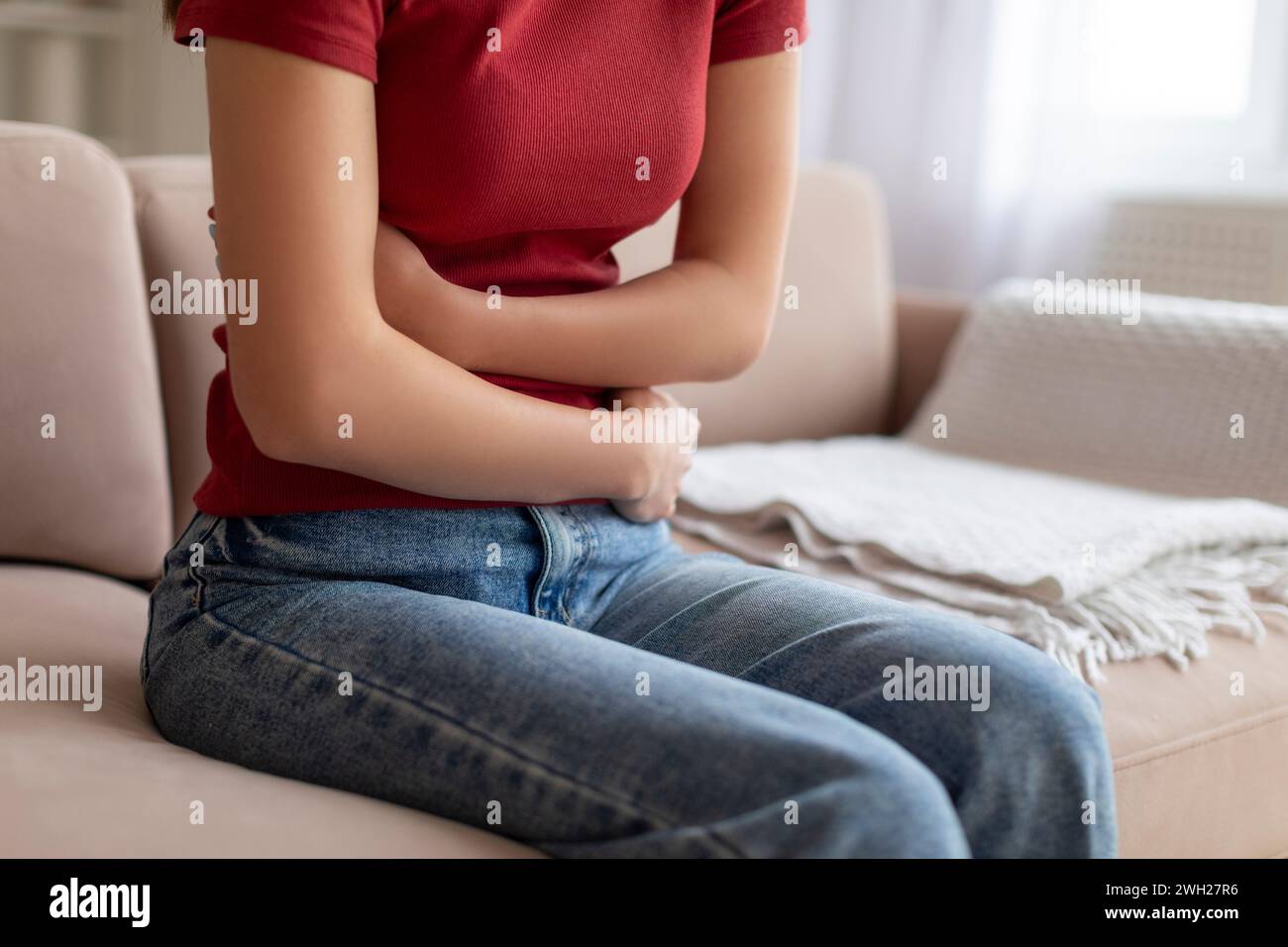 Uncomfortable young woman embracing her abdomen, feeling acute stomach ...