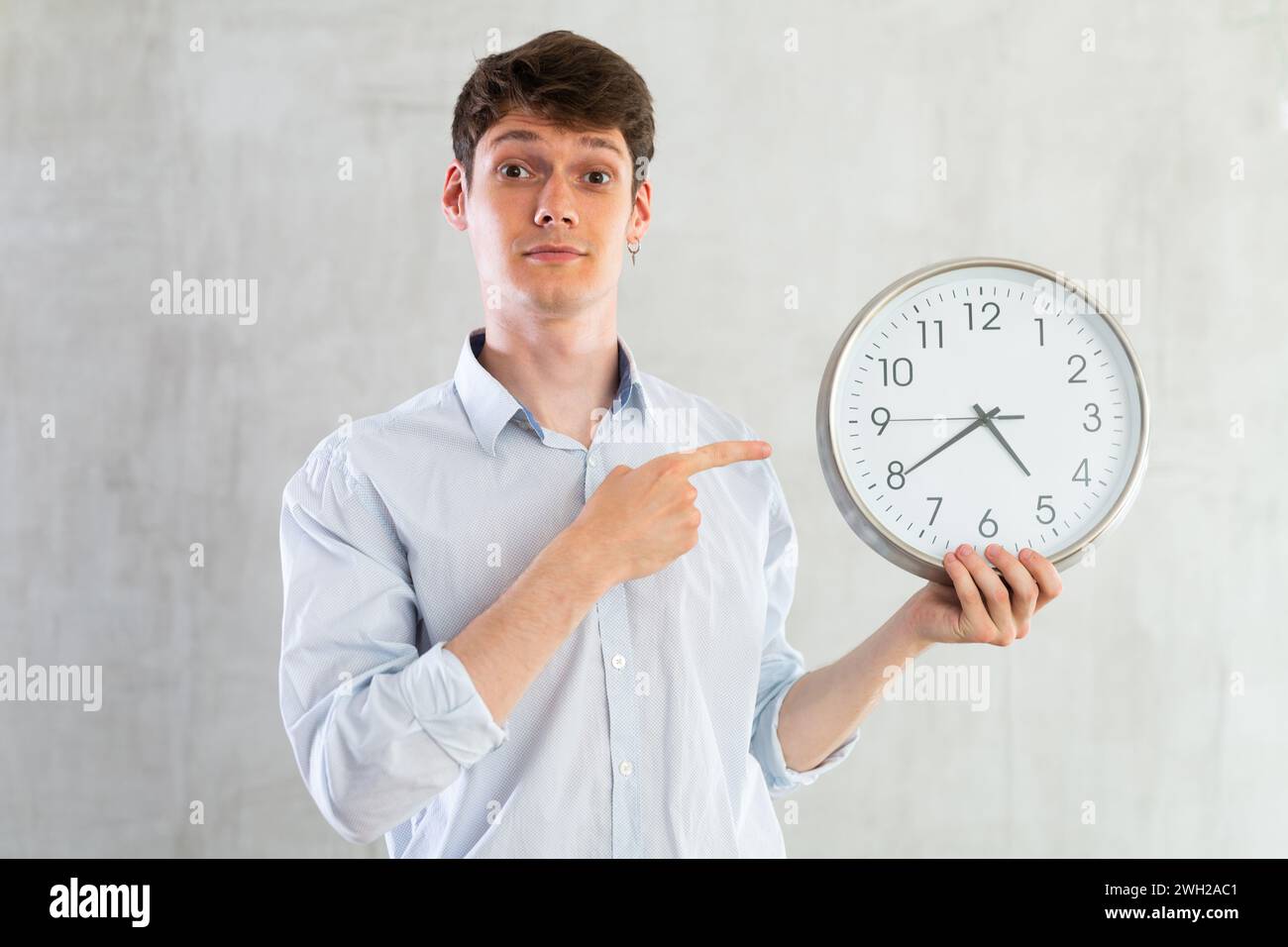 Man with a round big clock in his hands expresses various emotions ...
