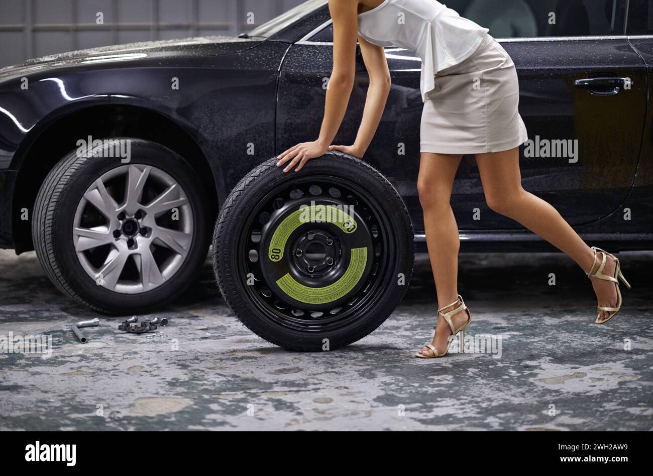 Woman, tyre and change for car repair with heels in parking garage or ...
