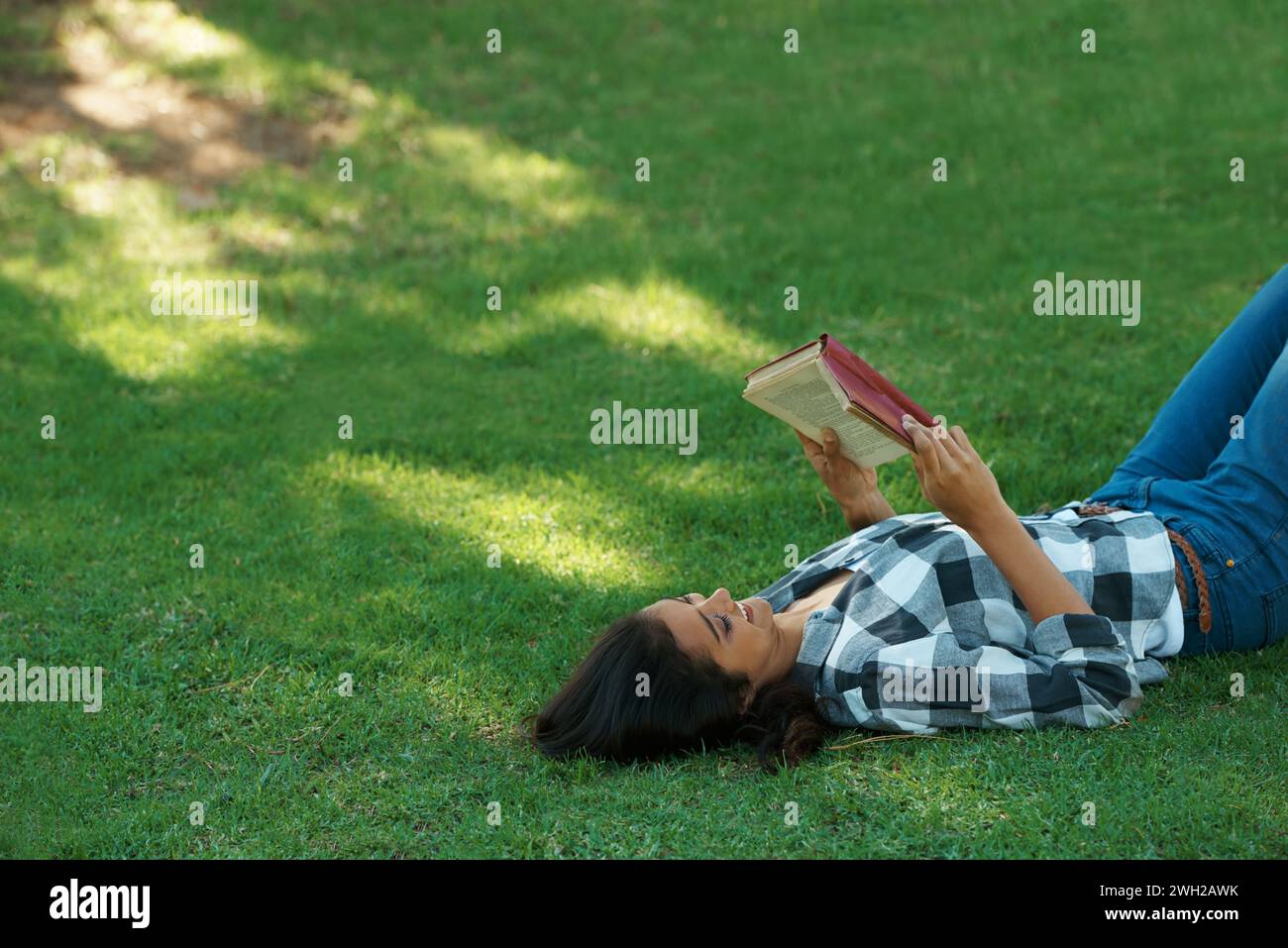 Woman, knowledge and reading book on grass, literature and smiling for ...
