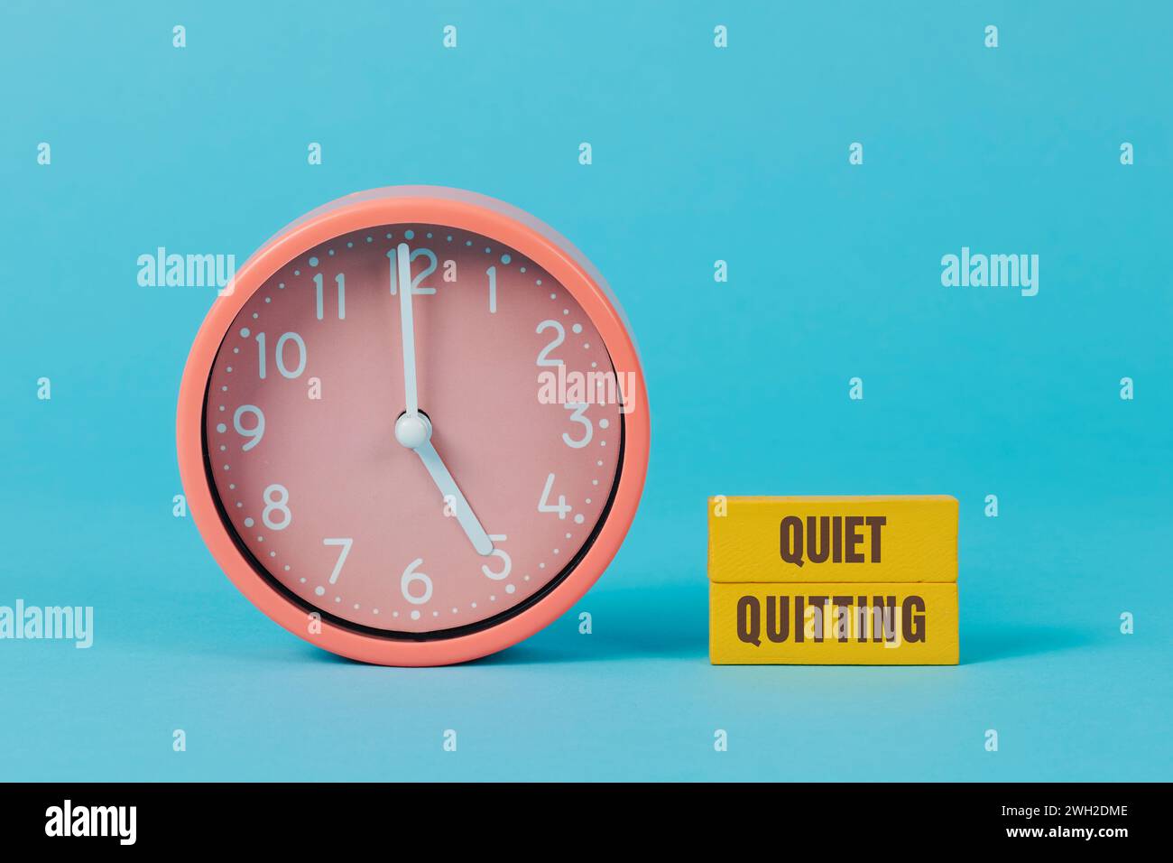 a pink clock striking five and the text quiet quitting written on two ...