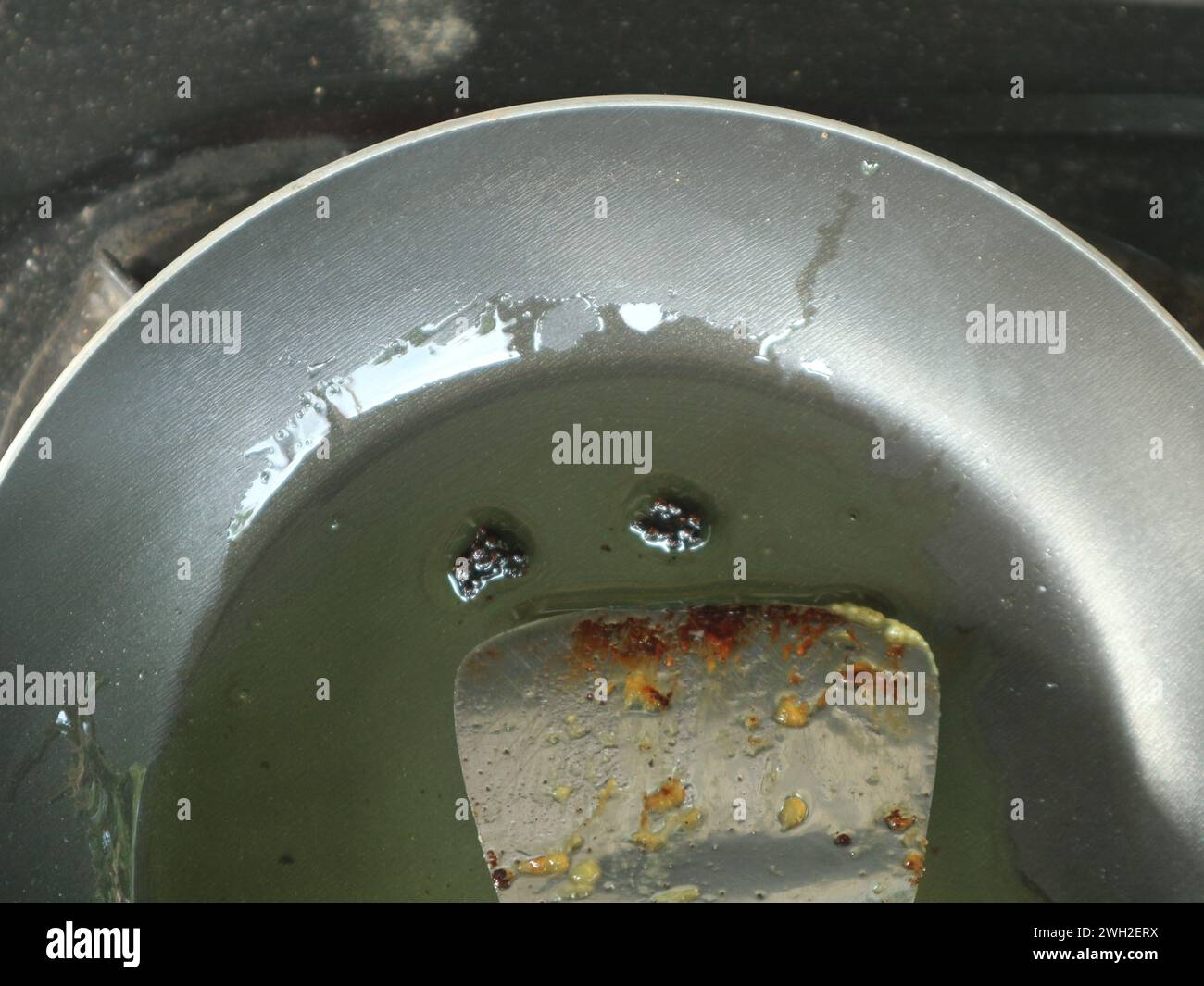 The container used for frying still has used oil and a spatula left ...