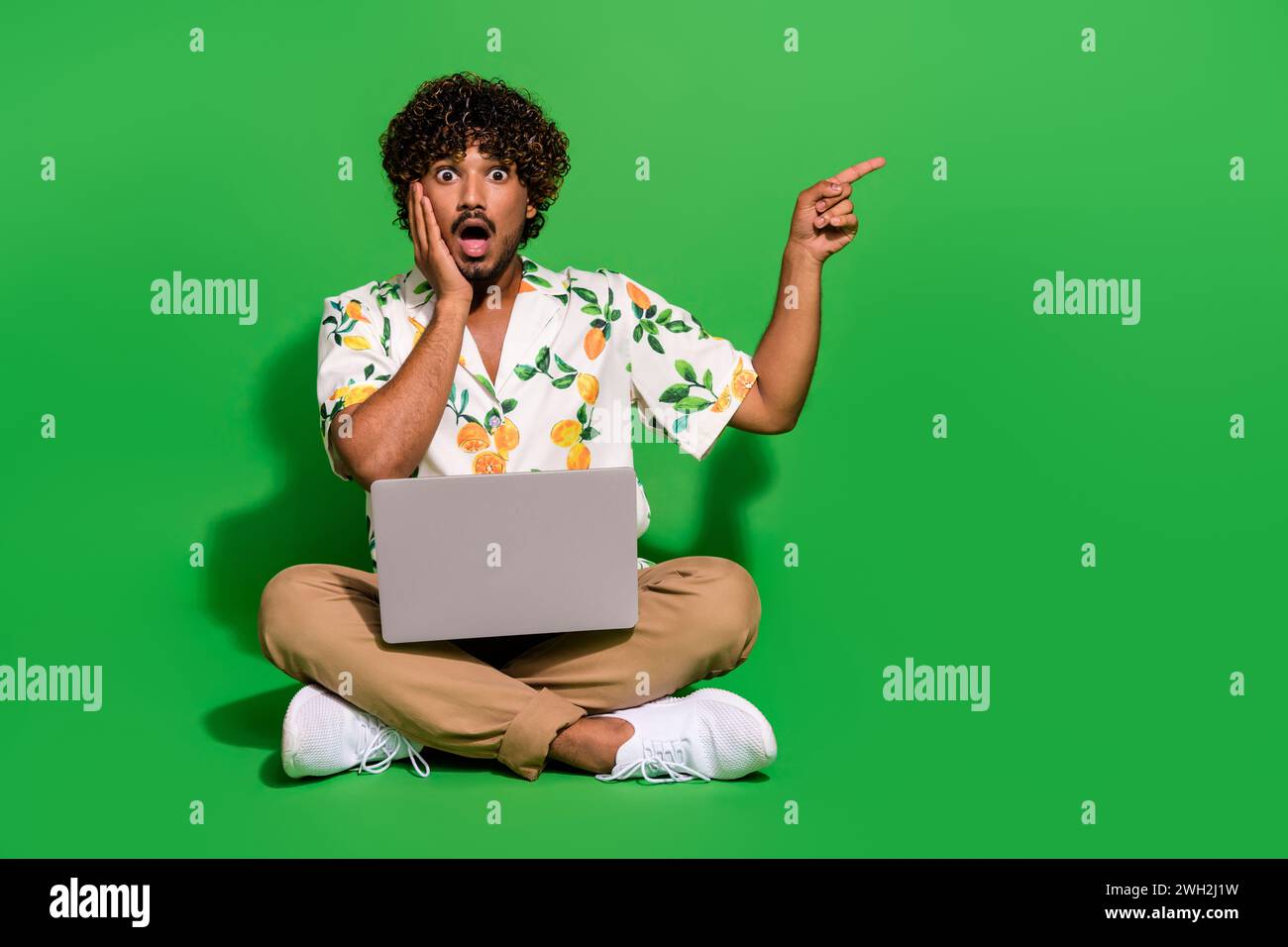 Full body photo of man sit floor shocked point empty space netbook ...