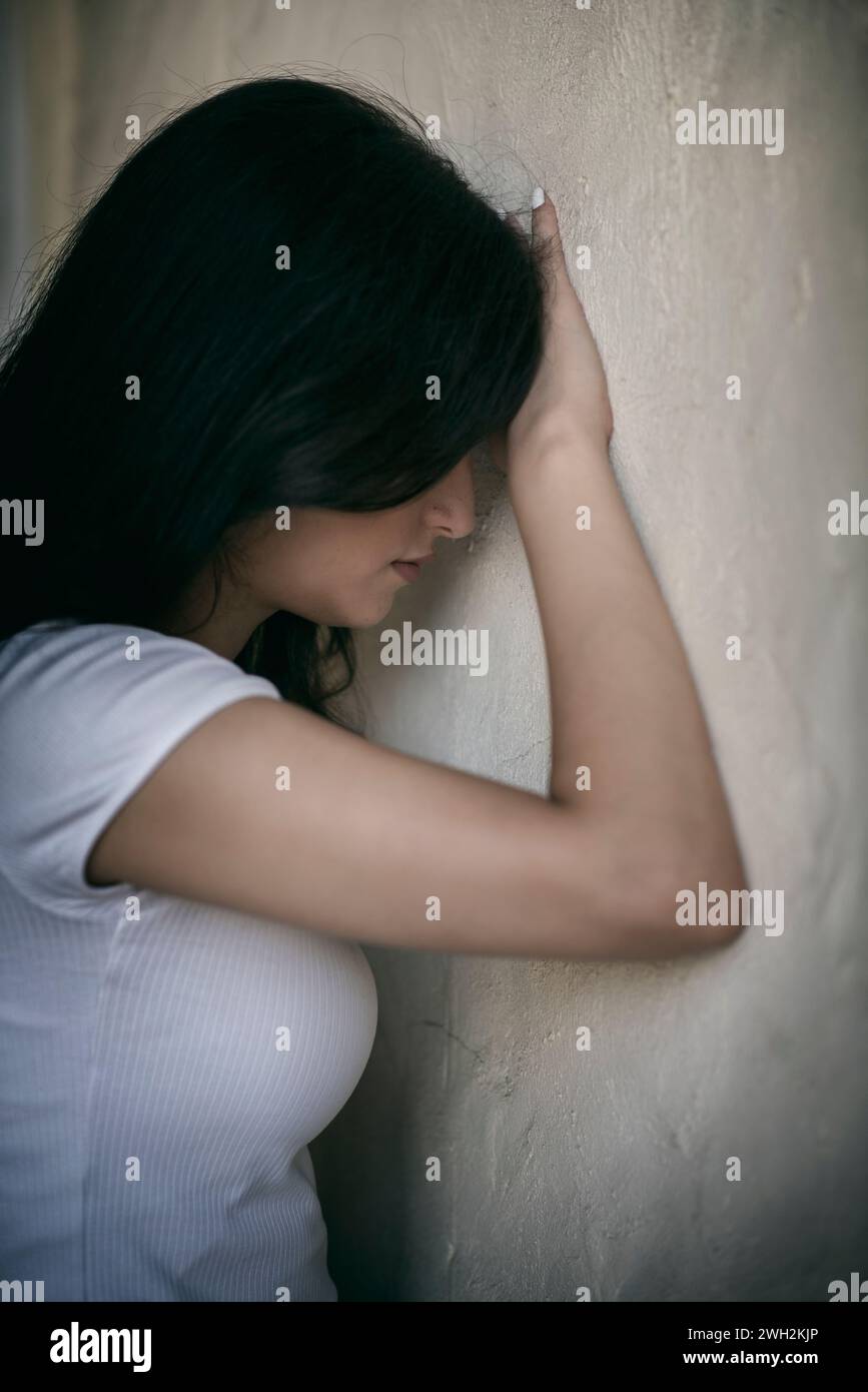 Sad woman leaning against the wall Stock Photo - Alamy
