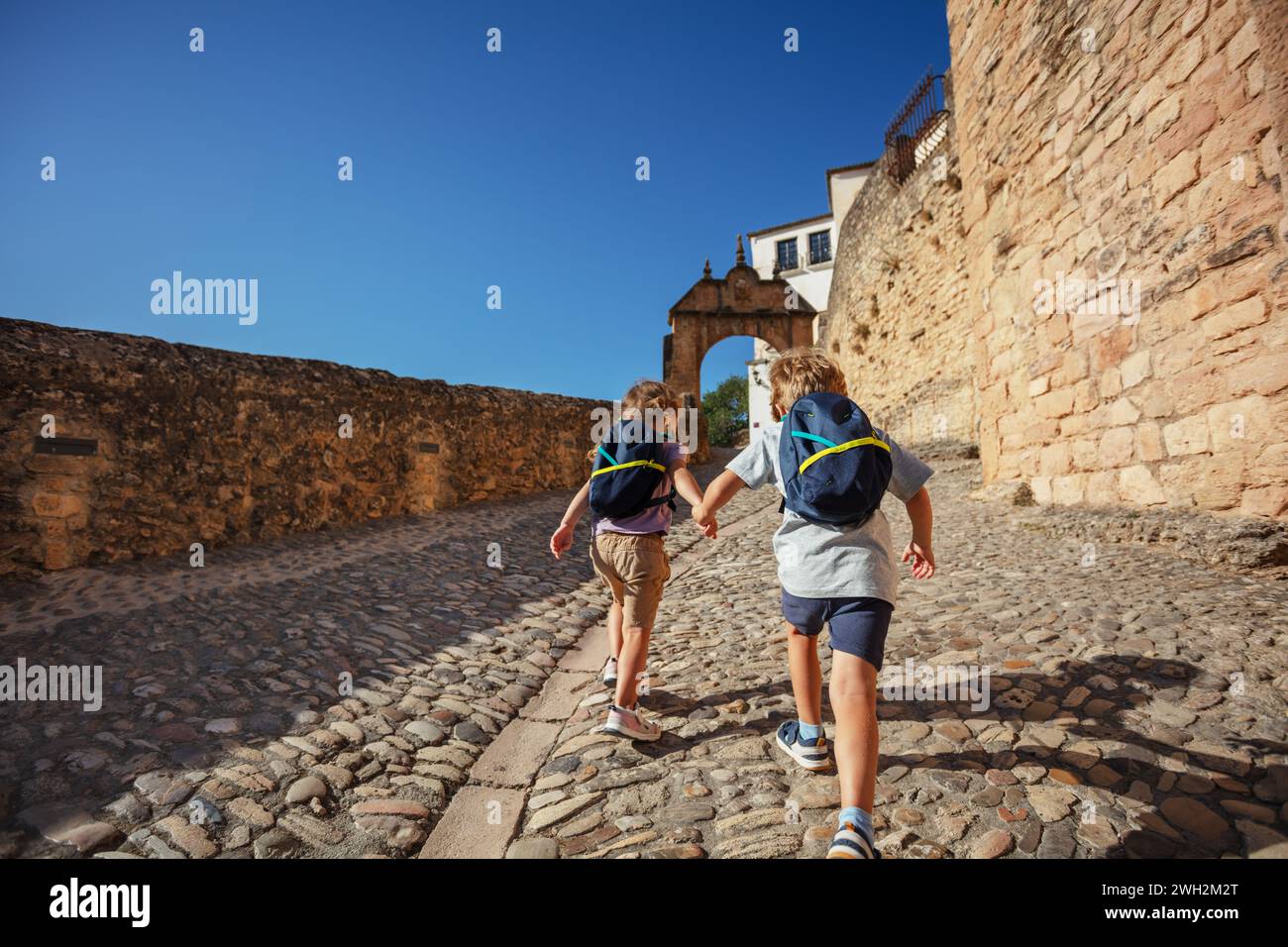Two kids with backpacks running in walls of old Ronda, Spain Stock ...
