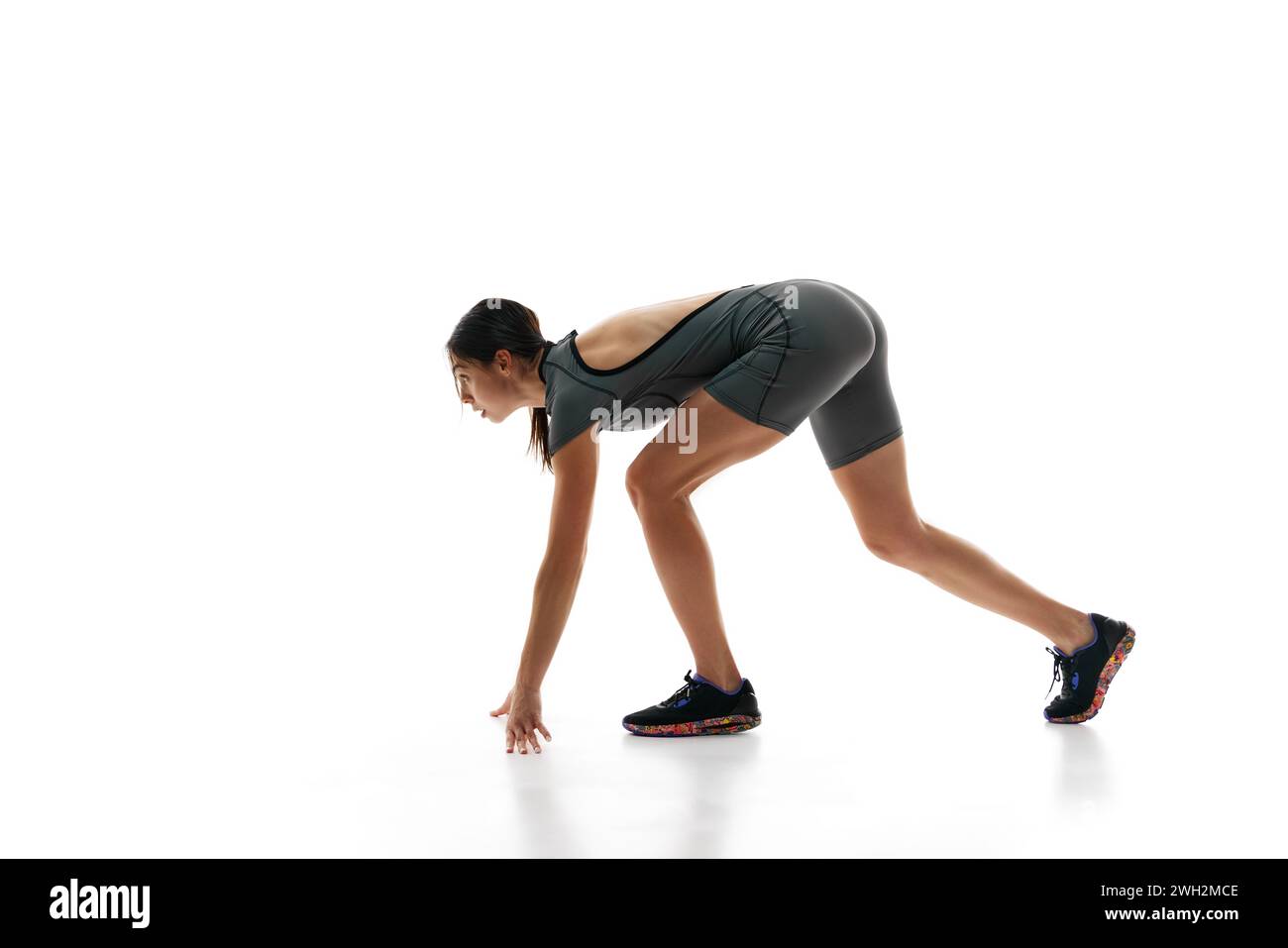 Ready, steady, go. Female runner athlete in grey jumpsuit, sportswear ...