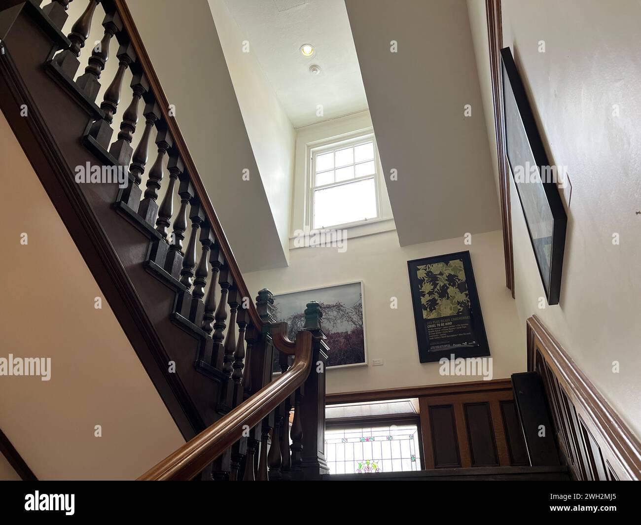 Upward look on a staircase with wooden banister. Windows are on each ...