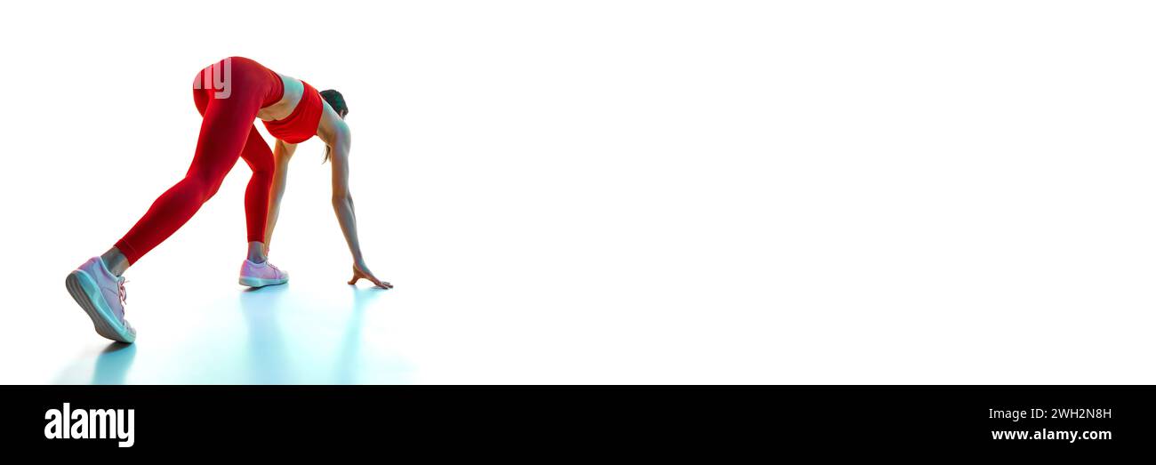 Ready, steady, go. Female runner athlete in red sportswear training ...