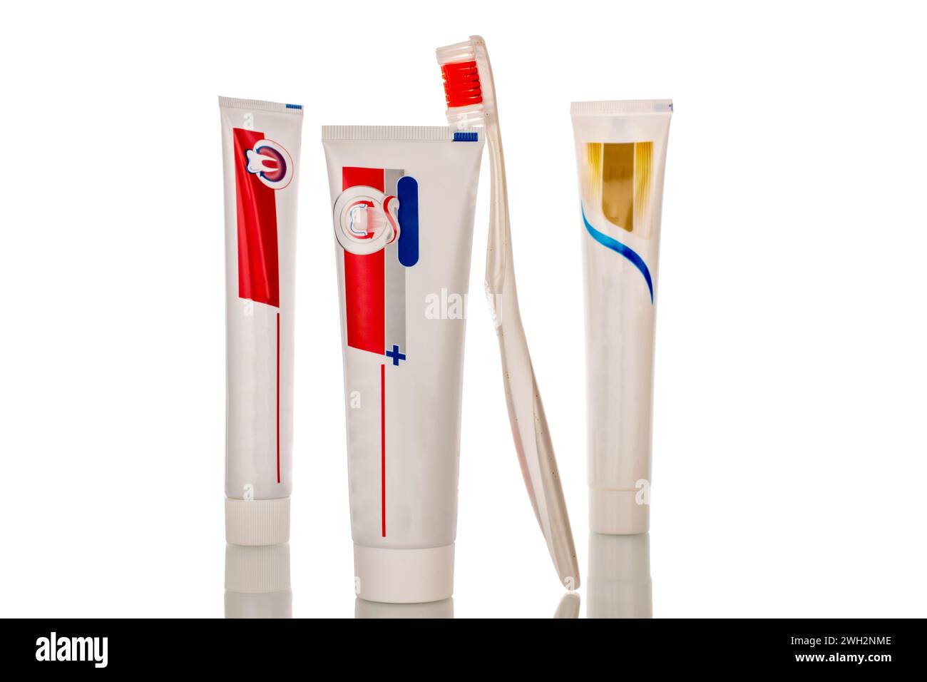 One toothbrush and three tubes of toothpaste, macro, isolated on white ...