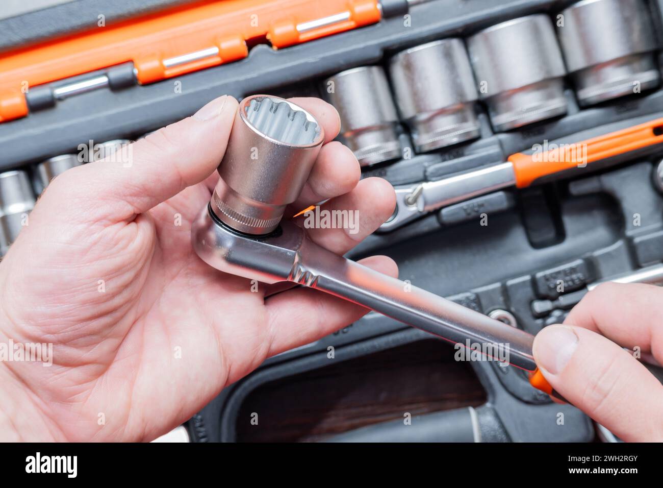 Hands of a man holding a ratchet wrench in the background you can see ...