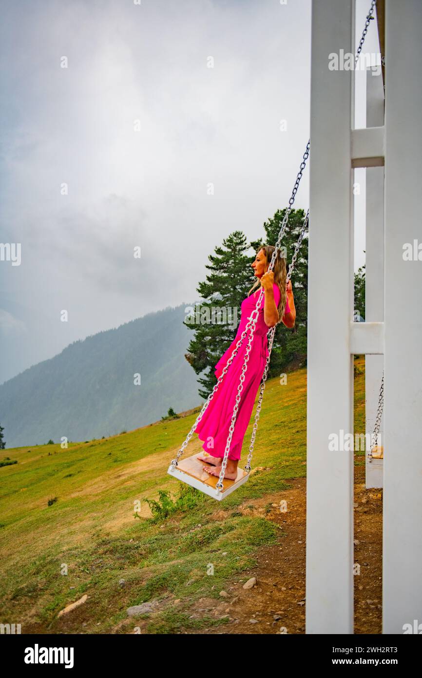 Chasing the swinging sun, a girl in a pink dress on a swing Stock Photo ...
