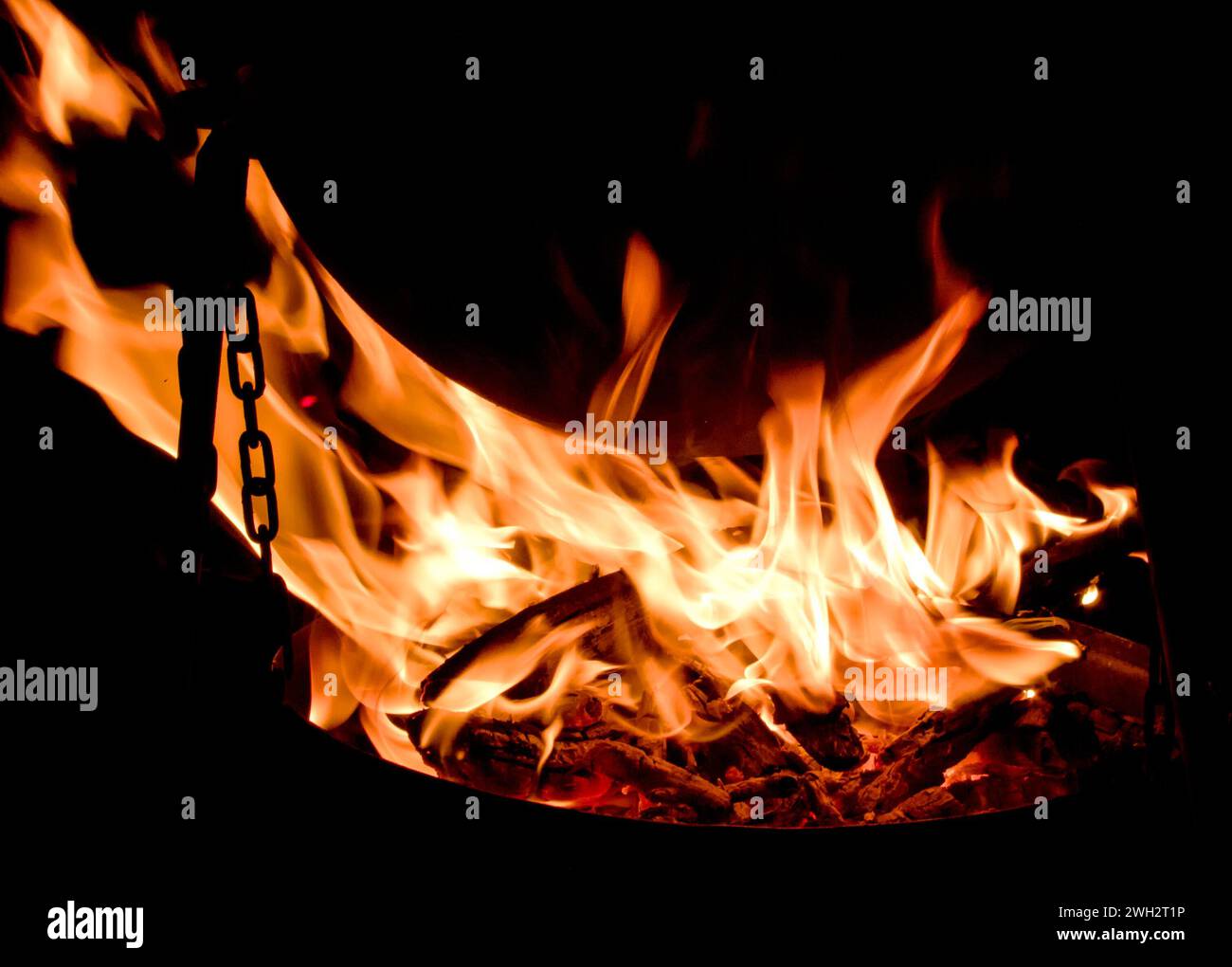 Cooking on a cauldron on a fire. Flames of fire in the dark Stock Photo ...