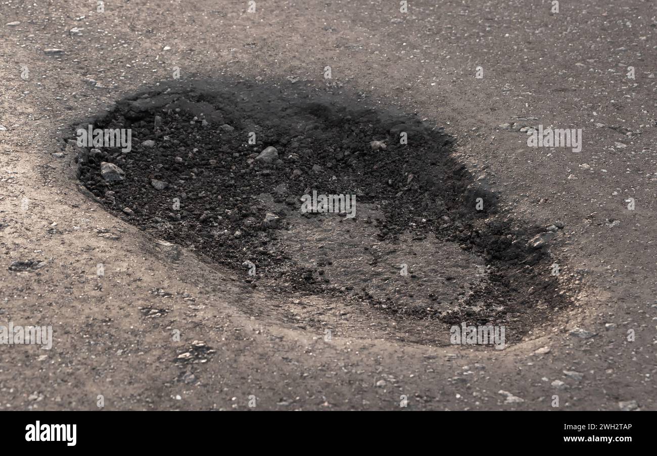 Deep pit on the road. Poor condition of asphalt pavement on the road ...