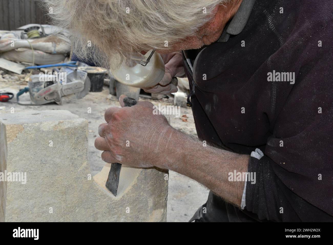Stone mason carving a detail in bath stone to be used on the renovation ...