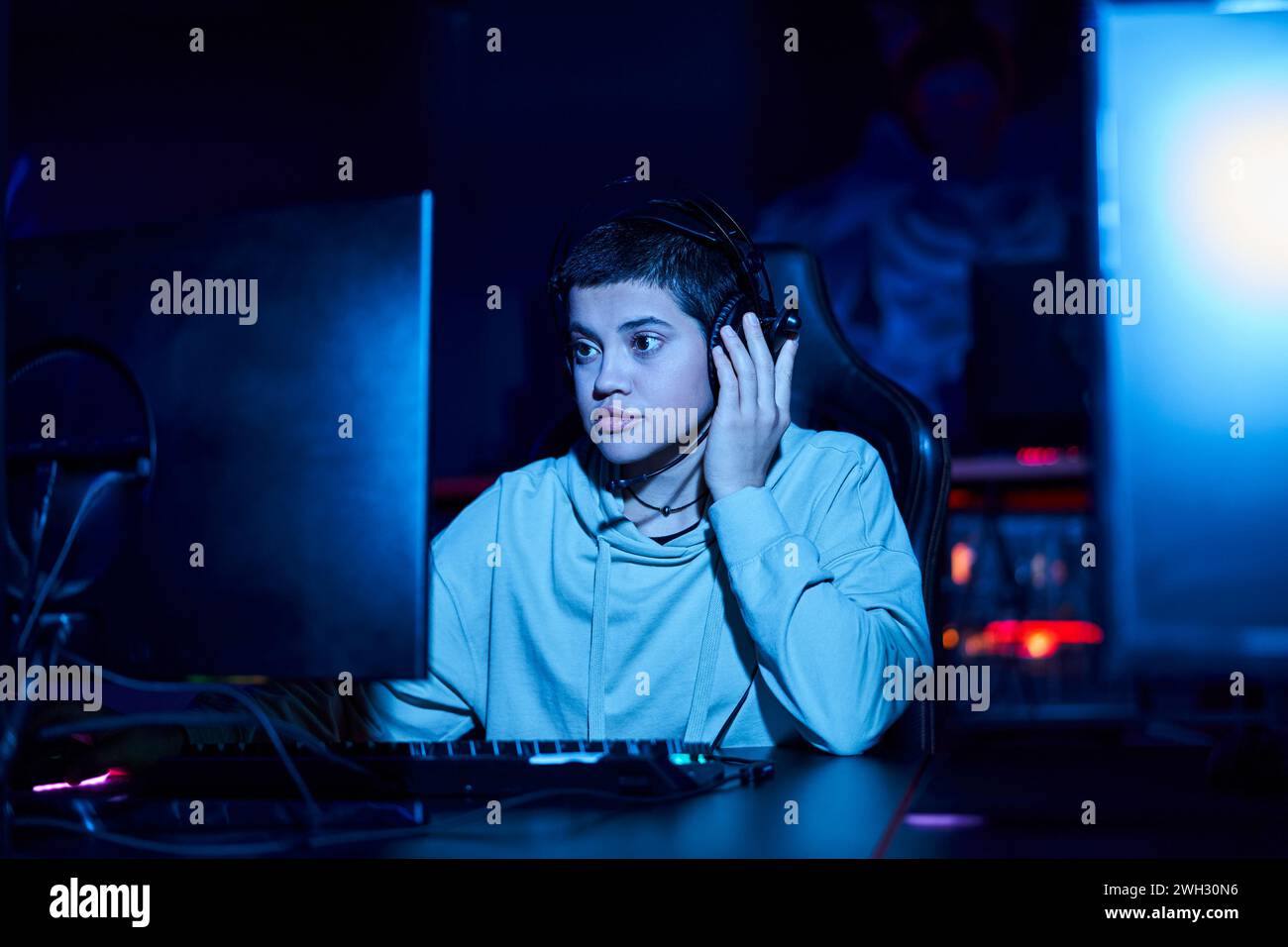 focused young gamer looking at computer monitor while playing game in a ...