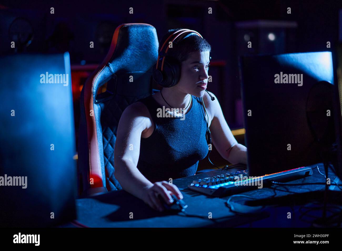 focused gamer in headphones looking at computer monitor while thinking ...