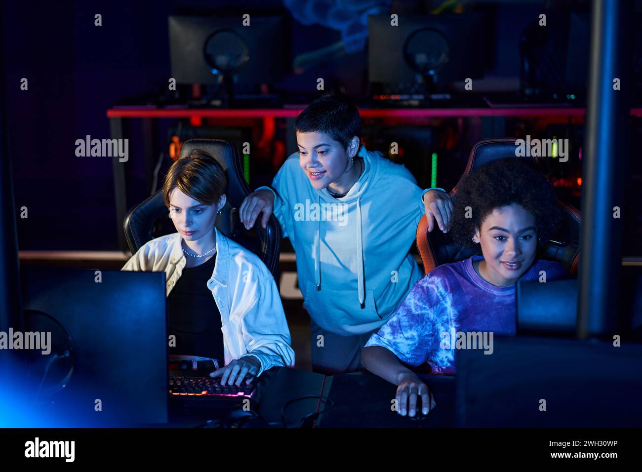 Diverse women engaged in cybersport games, using computers and smiling ...