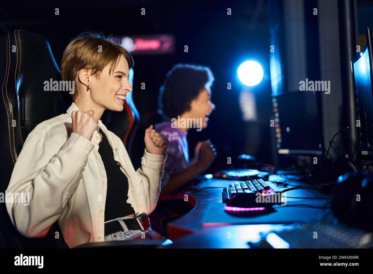 focus on cheerful woman with short hair looking at computer monitor ...