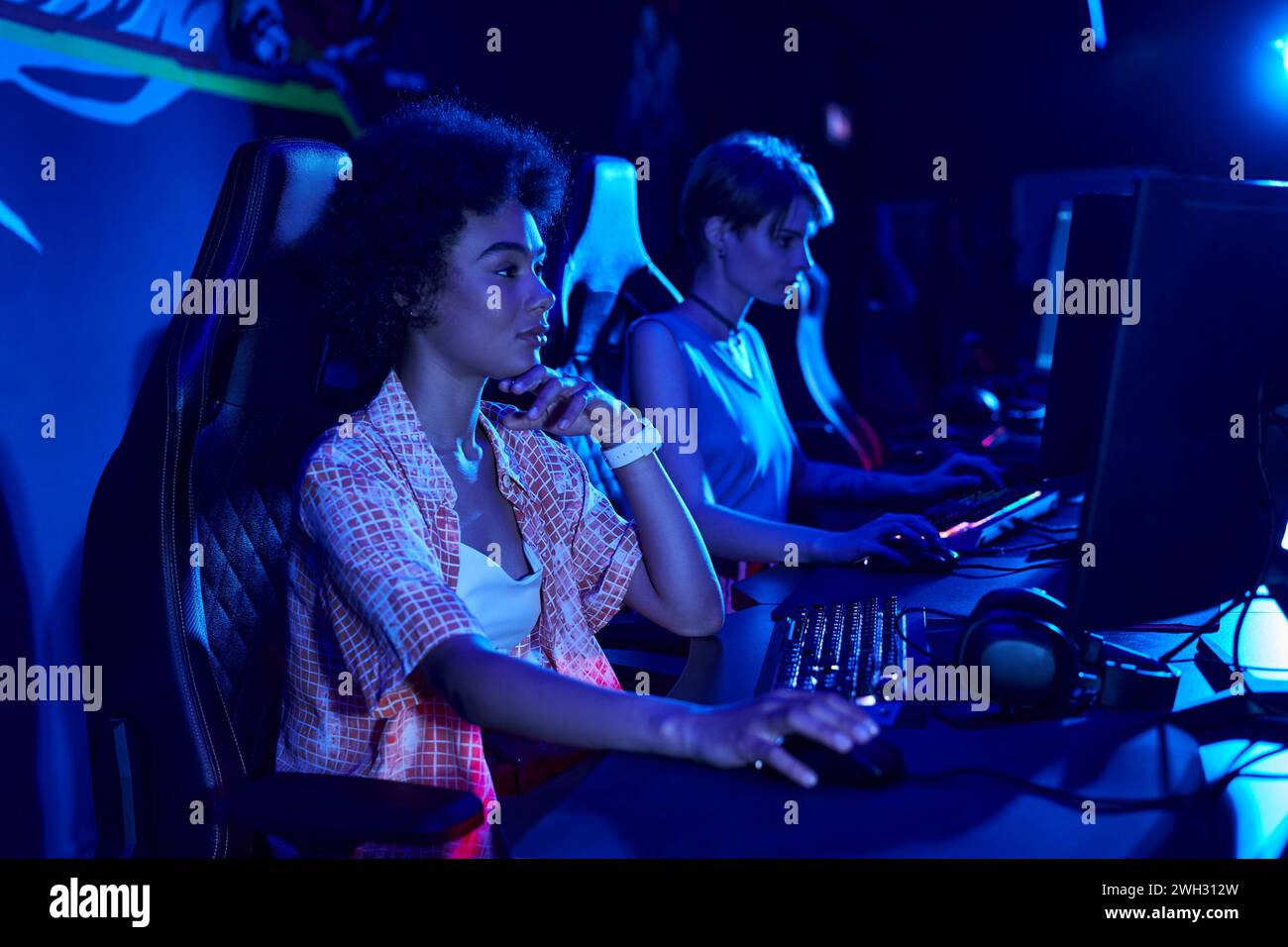 focus on serious african american woman gaming intensely in a blue-lit ...