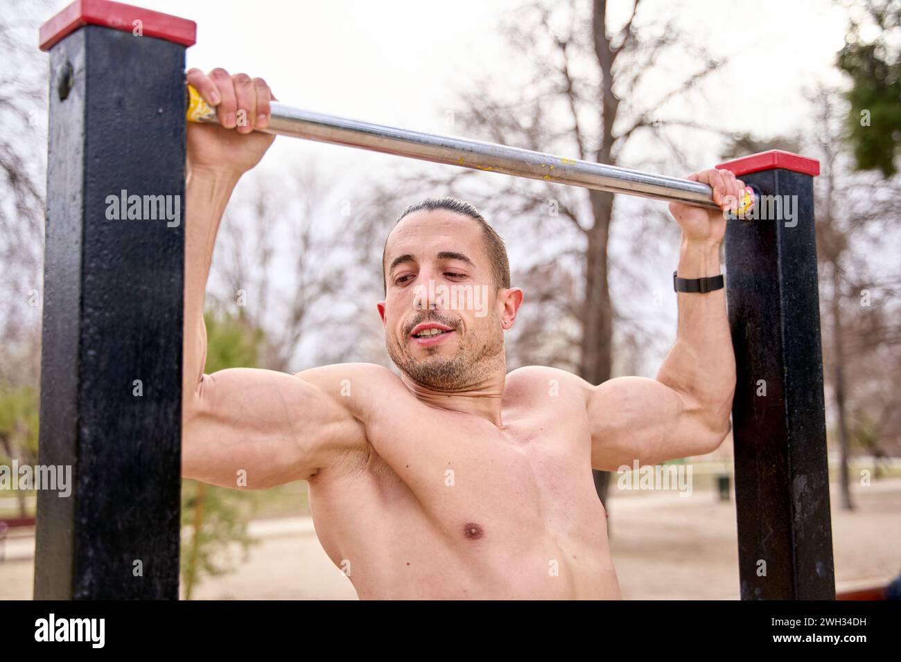 Fitness Man Doing Pull-Ups At The Bars In A City Park. Front view of a ...