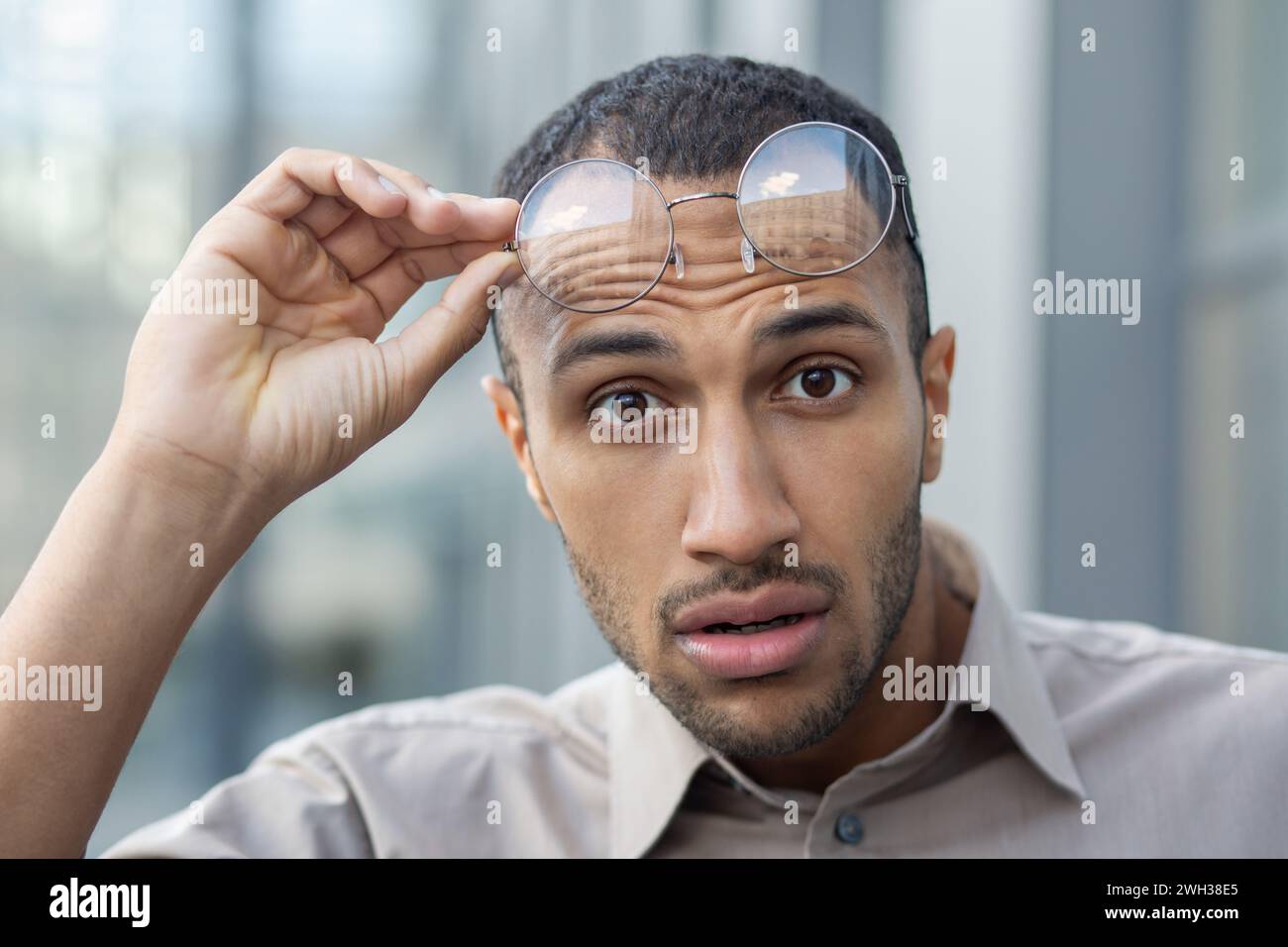 Portrait of surprised arab man looking amazed at camera and taking off ...