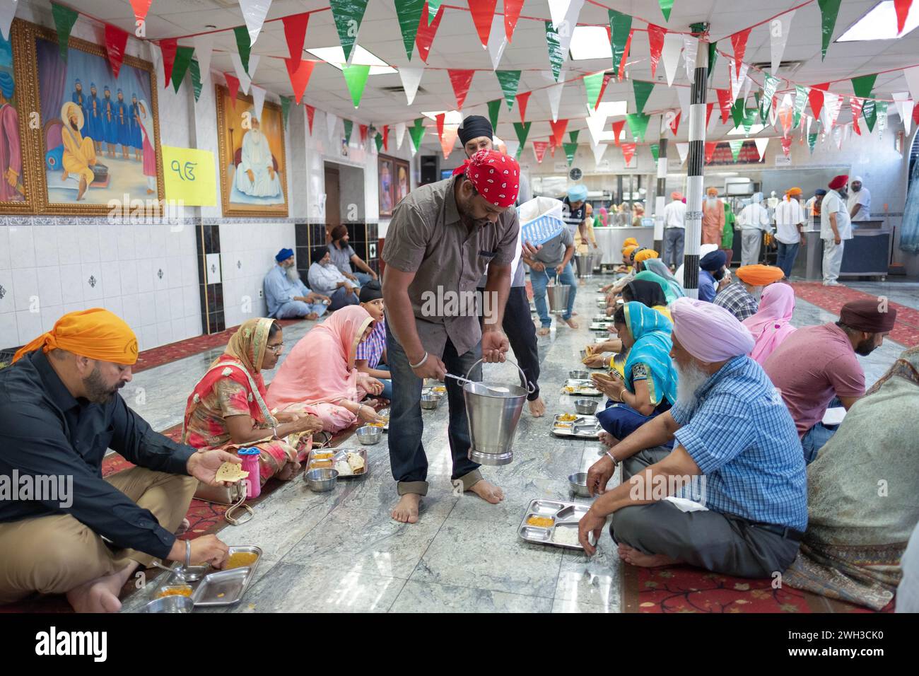 Men and women eat a vegetarian meal at a langar in a Sikh temple in ...
