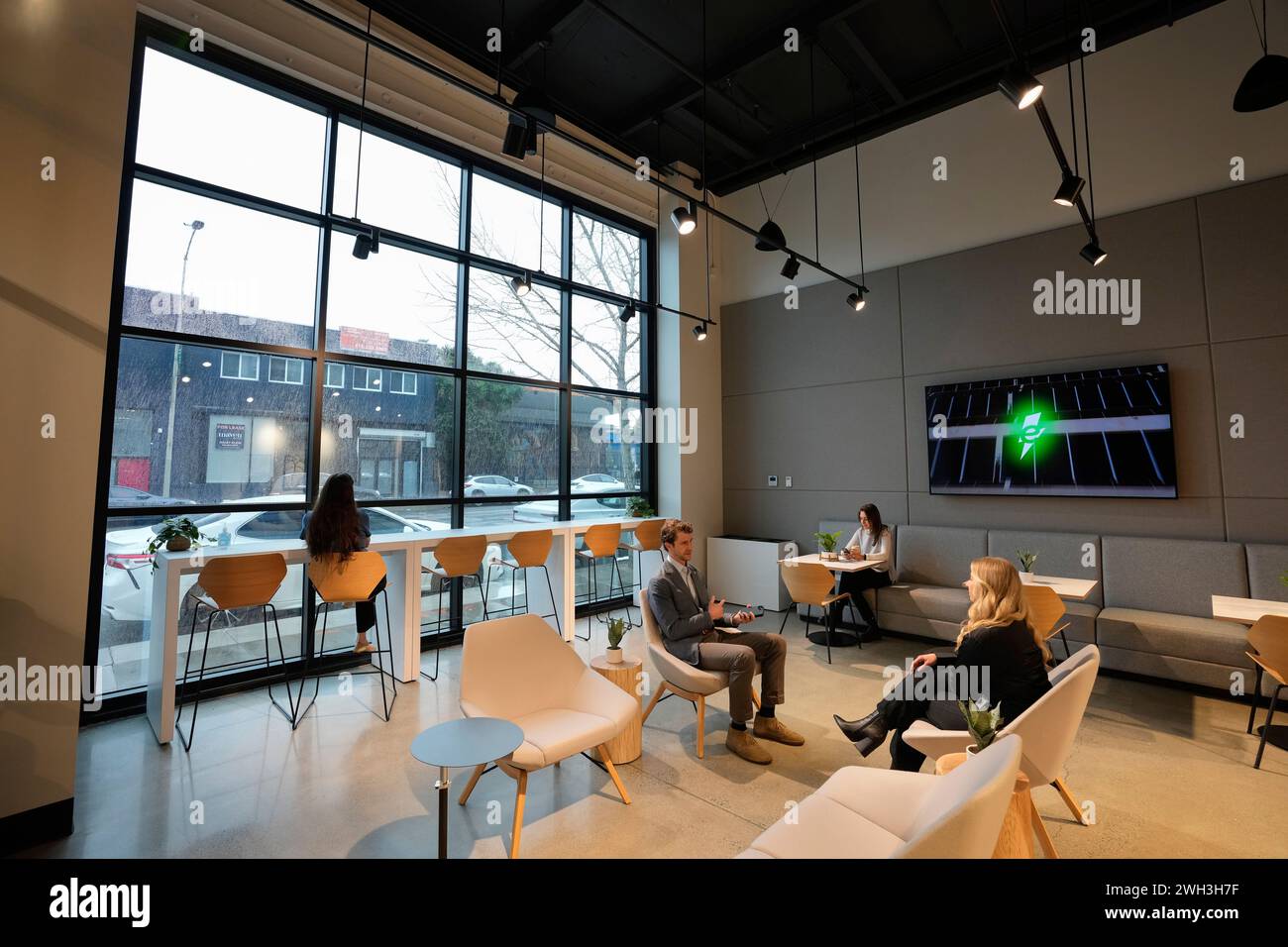 People sit in a waiting lounge at the new Electrify America indoor ...