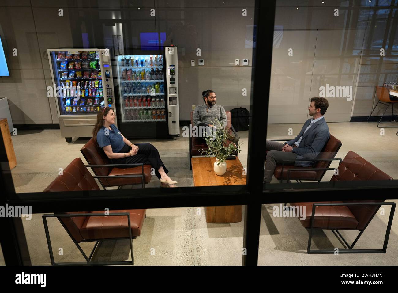 People sit in a waiting lounge at the new Electrify America indoor ...