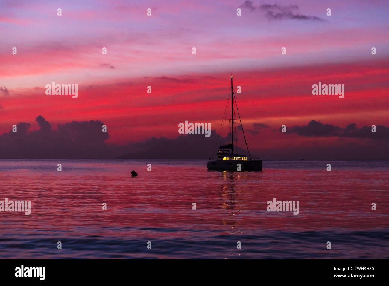 Silhouette of catamaran yacht under red sky at sunset. Mahe island ...