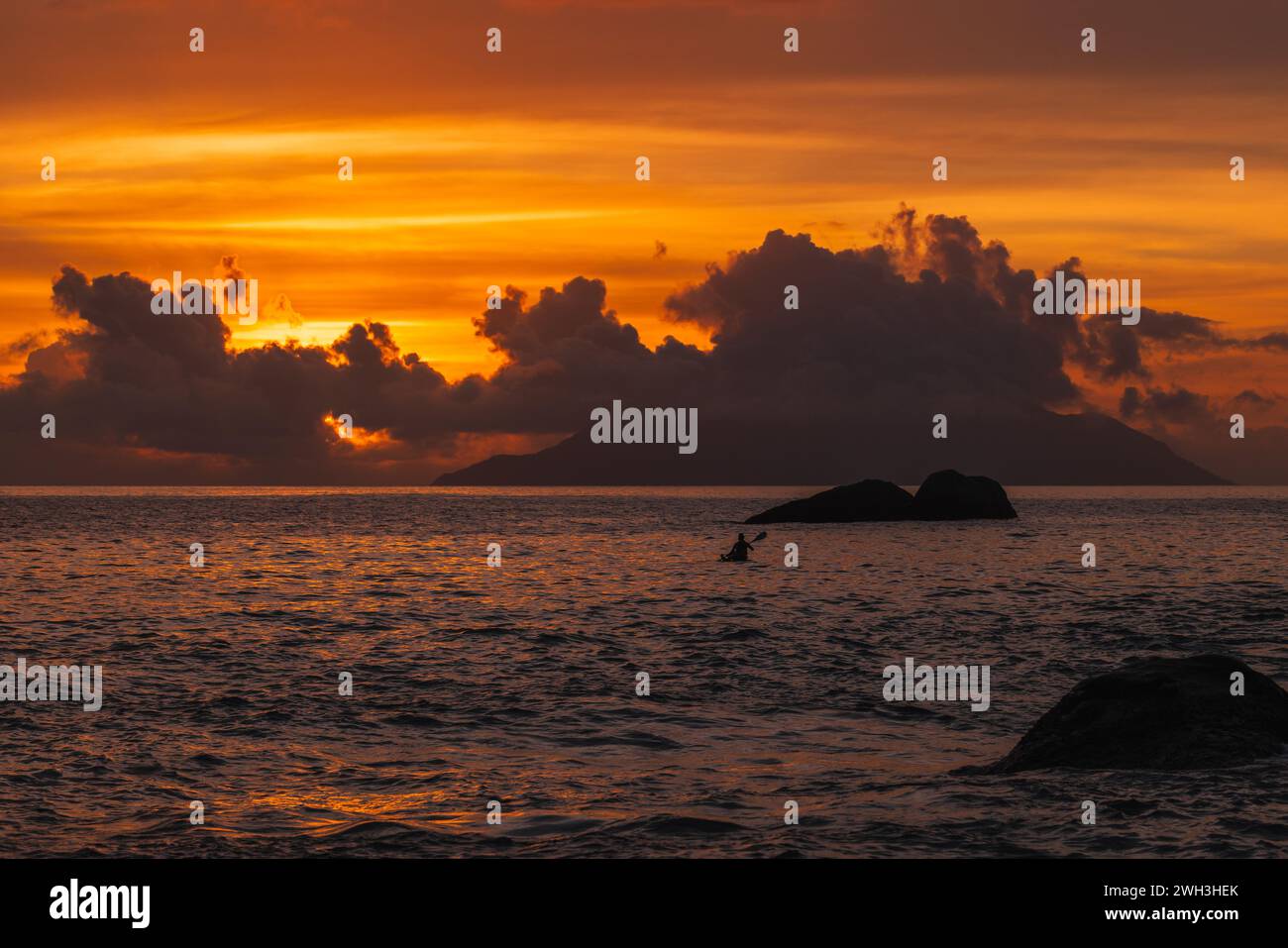 Ocean view with silhouette of a rowboat under sunset sky. Mahe island ...