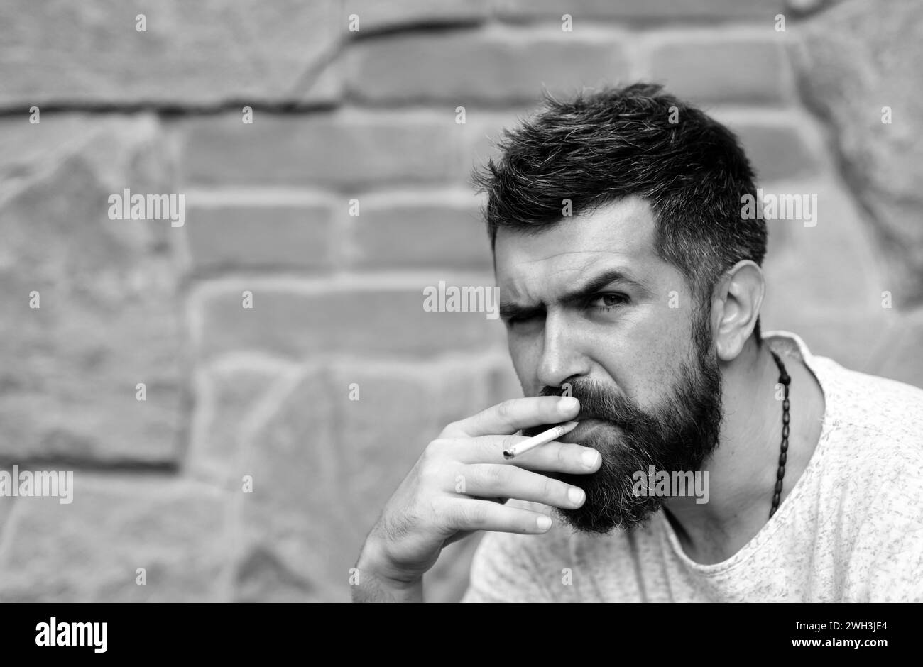 Hipster brutal man smoking cigarette. Handsome guy smoking outside in ...