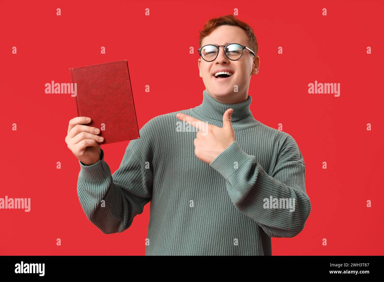 Emotional young man pointing at book on red background Stock Photo - Alamy