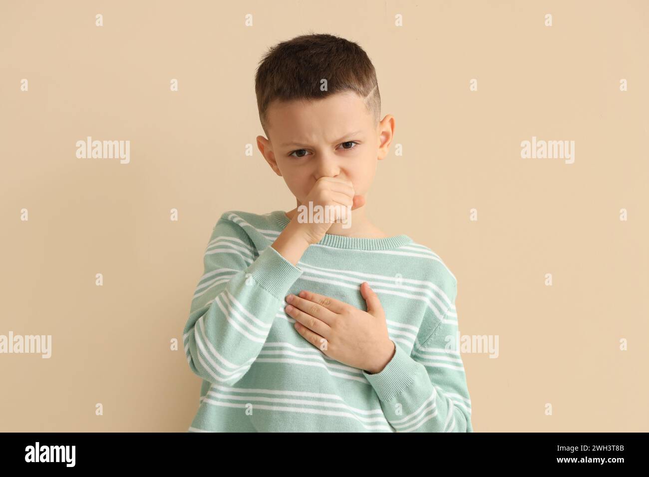 Ill little boy coughing on beige background Stock Photo - Alamy