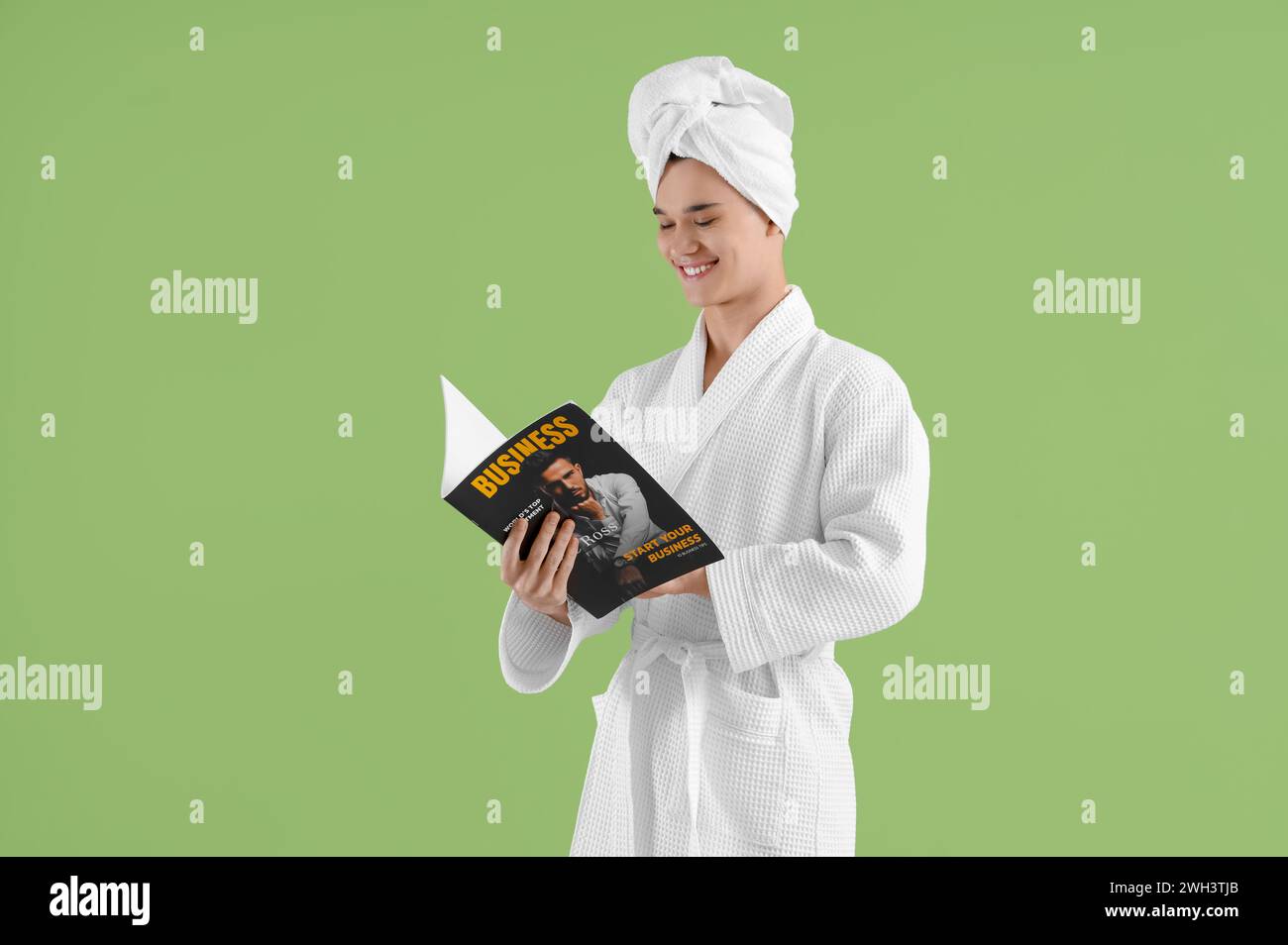 Teenage boy in bathrobe reading magazine after shower on green ...