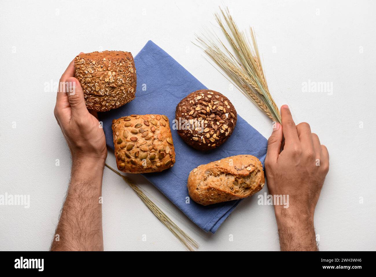 Male hands with delicious buns and wheat ears on napkin against white ...