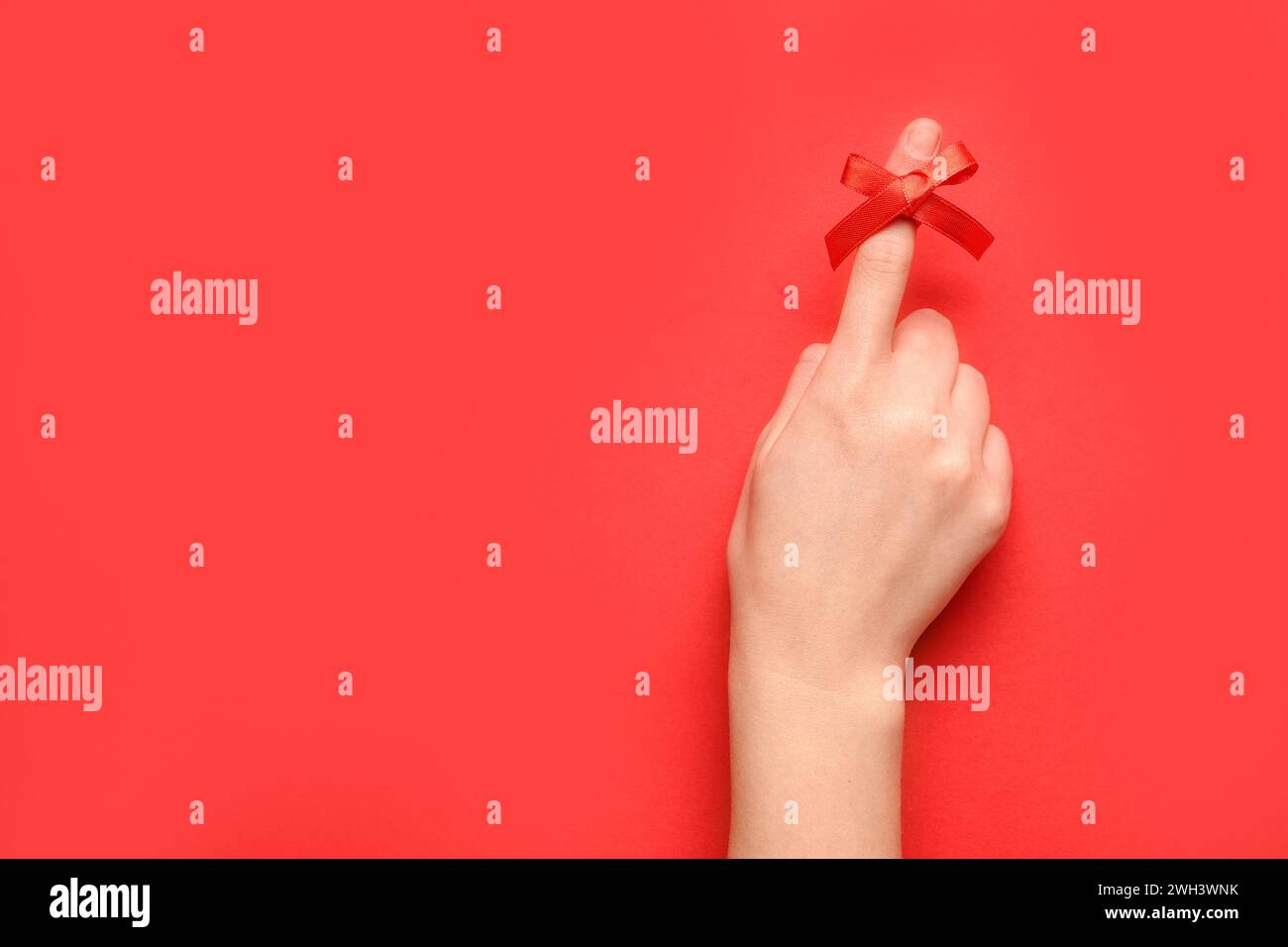 Female hand with red bow on index finger against red background ...